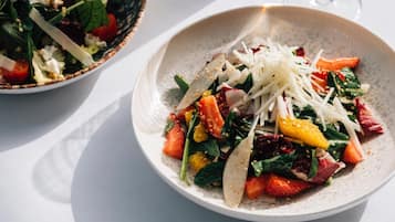 Duas saladas em pratos, uma garrafa de vinho e copos sobre uma mesa.