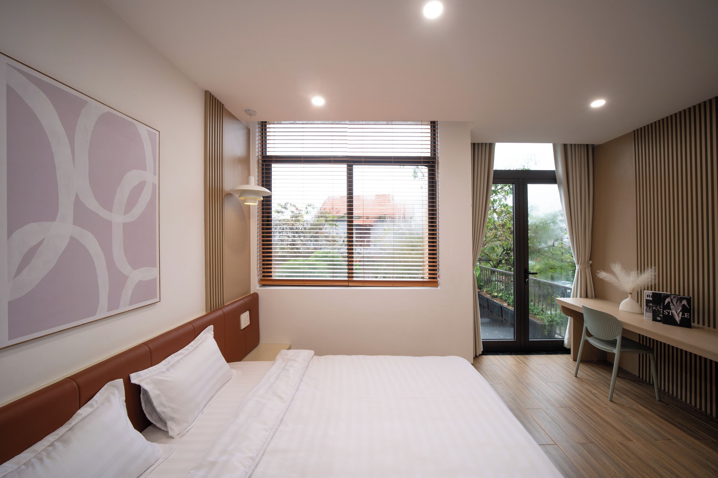 Quarto de hotel moderno com uma cama grande, uma escrivaninha e vista para o exterior.