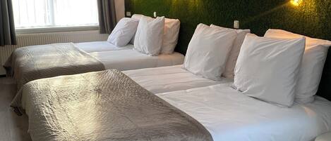 Quarto de hotel com duas camas, um ventilador de teto e uma parede verde com luzes fixadas.