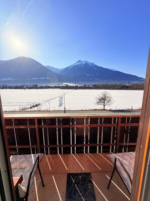 Uma varanda com vista para uma paisagem coberta de neve e montanhas.