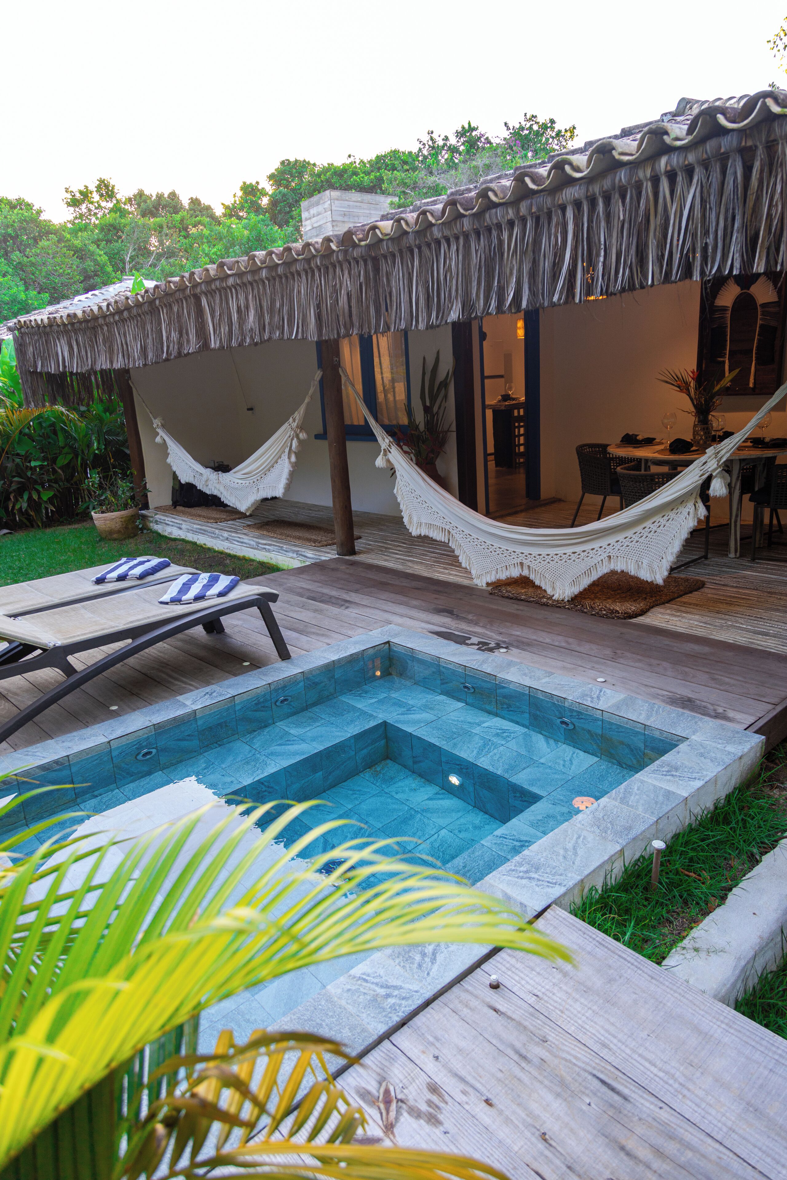 Uma área de piscina com uma rede, espreguiçadeiras e um espaço para refeições.