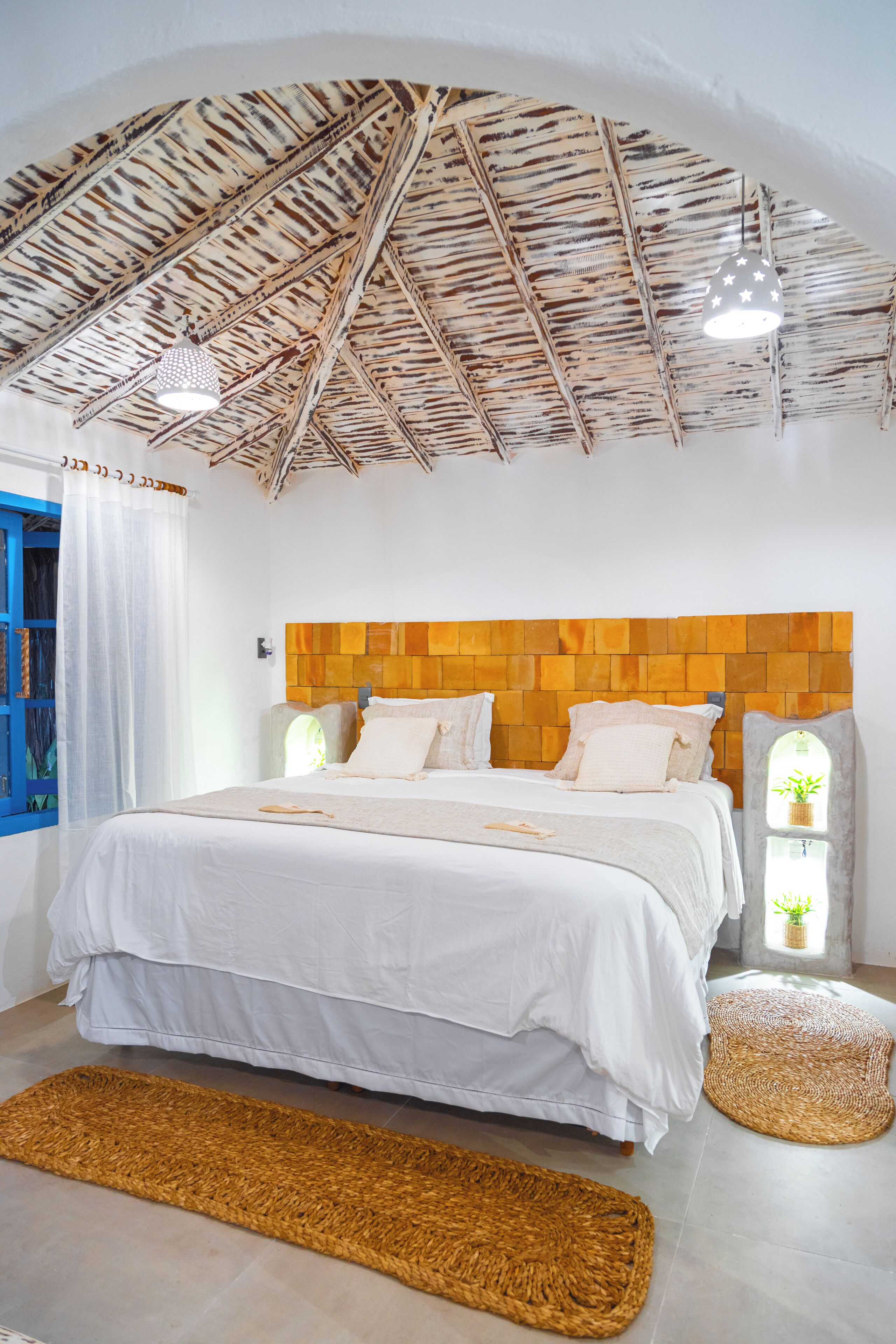 Quarto com cama, teto de tear e janela com vista.