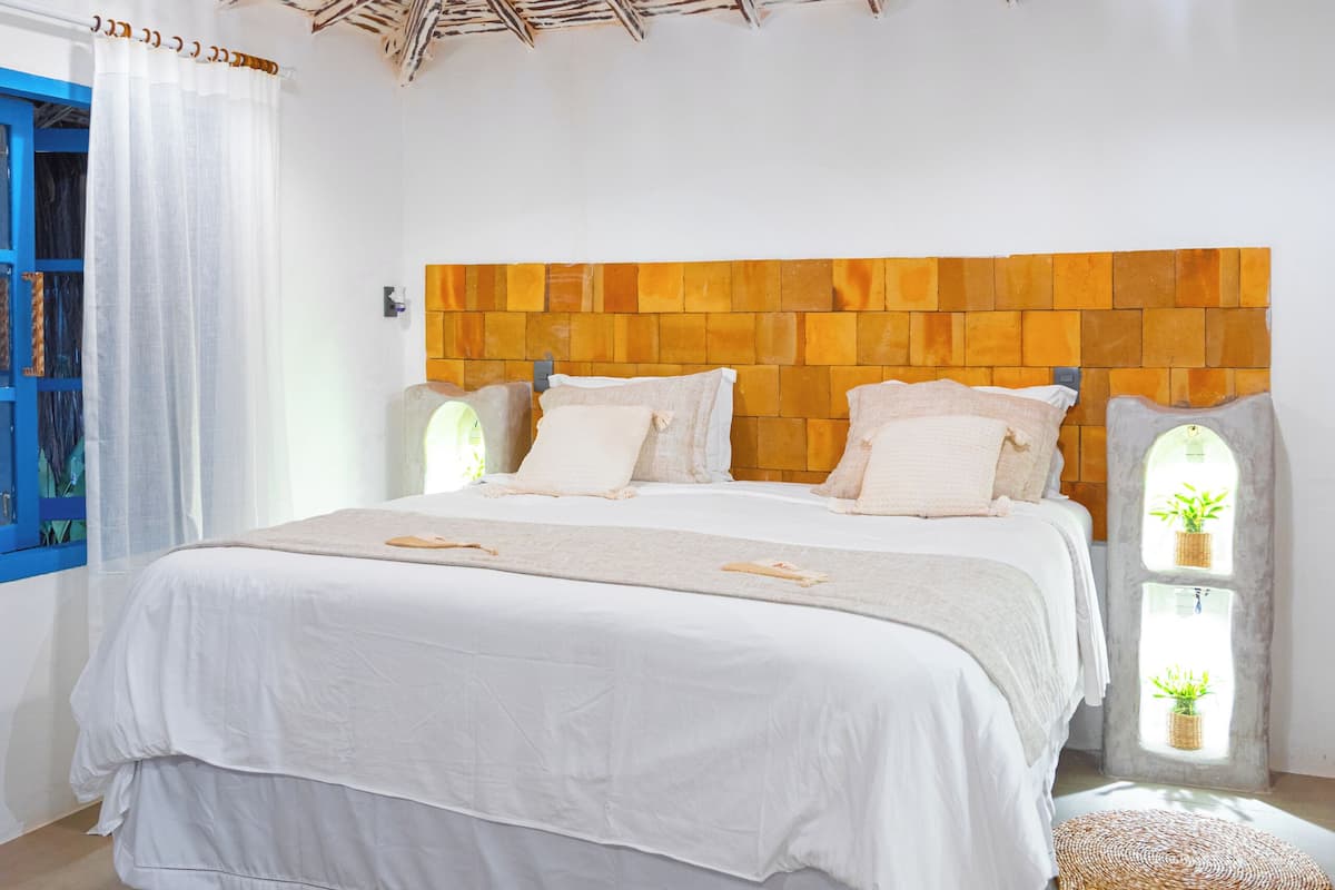 Quarto com cama, teto de tear e janela com vista.