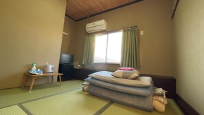 Um quarto pequeno com esteiras de tatame, televisão, aquecedor e janela com cortinas.