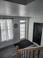 Um interior moderno com uma porta preta marcada com o número 4, uma porta branca e uma janela com cortinas leves.
