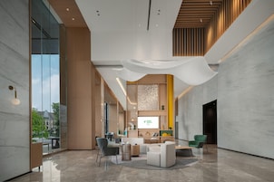 Um hall amplo com design moderno, com uma grande área de estar, um balcão de recepção e uma tela exibindo informações.