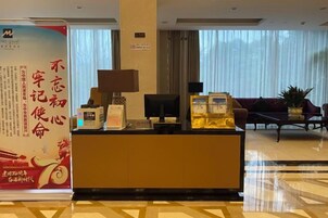 Uma área de recepção de hotel com balcão, televisão e um espaço de estar com sofá e mesa de centro.