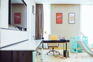Quarto de hotel com escrivaninha, cadeira e área de recreação infantil, incluindo um escorrega.