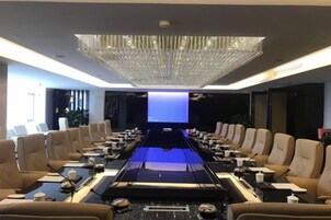 Sala de conferências com uma mesa comprida, cadeiras e uma tela grande.
