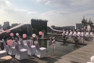 Espaço em terraço com cadeiras brancas e balões cor-de-rosa, com vista para a paisagem urbana.