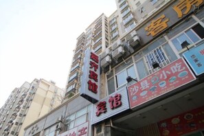 Edifício de vários andares com estabelecimentos comerciais no andar térreo, incluindo um restaurante e uma loja.
