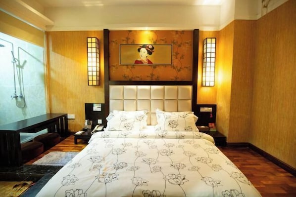 Quarto de hotel com uma cama grande, uma mesa, uma cadeira e uma televisão.