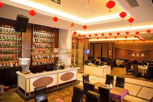 Um hall de hotel com balcão de recepção, área de estar e uma parede com garrafas de bebidas alcoólicas.