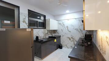 Uma cozinha moderna com micro-ondas embutido, eletrodomésticos de aço inoxidável e painel de fundo de mármore.