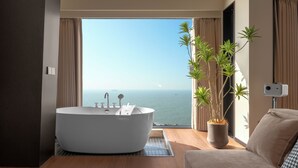 Um banheiro moderno com uma banheira grande, uma planta em vaso e vista para o mar.