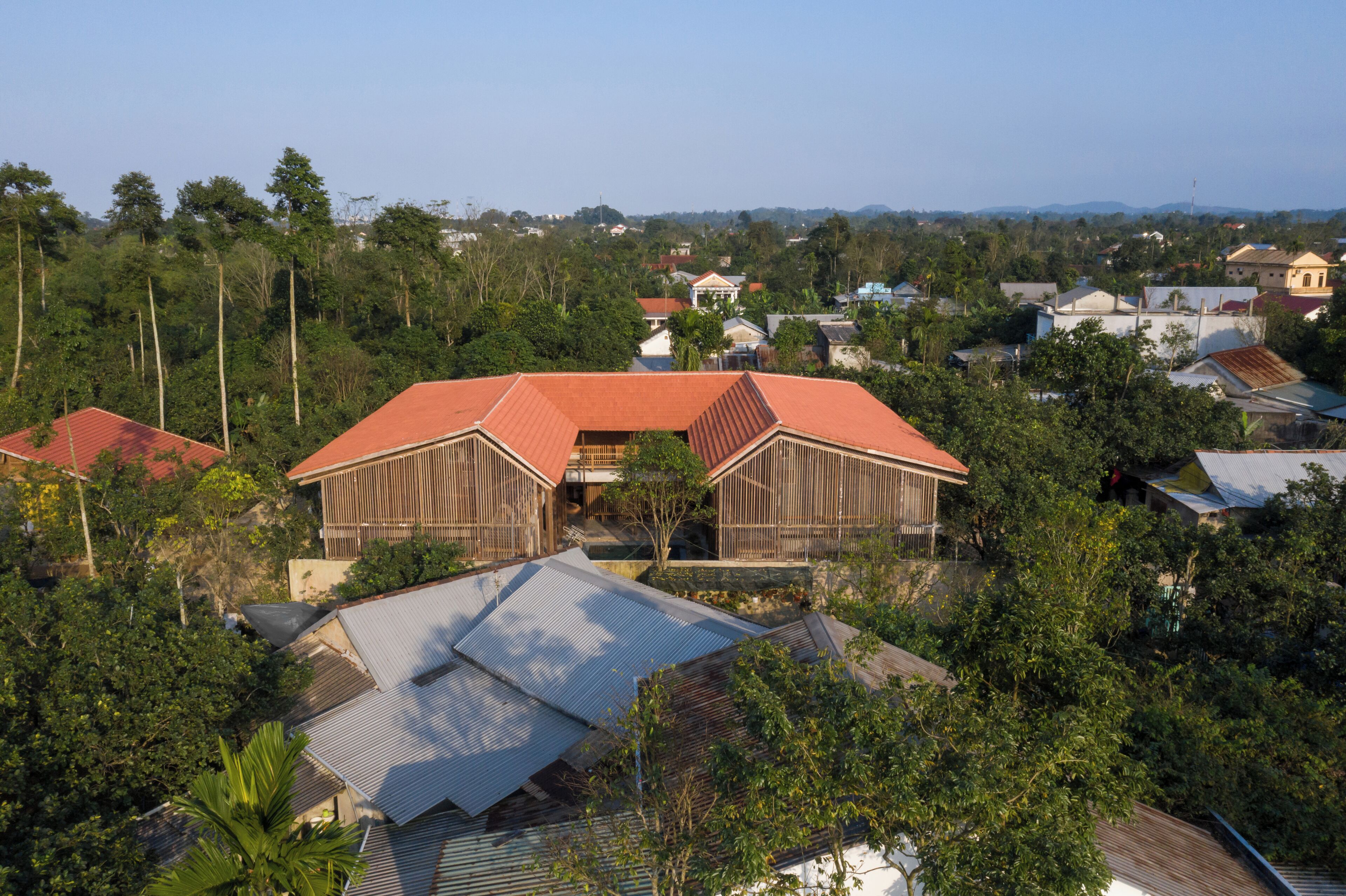 Um edifício grande com telhado vermelho, rodeado por árvores e outros edifícios.