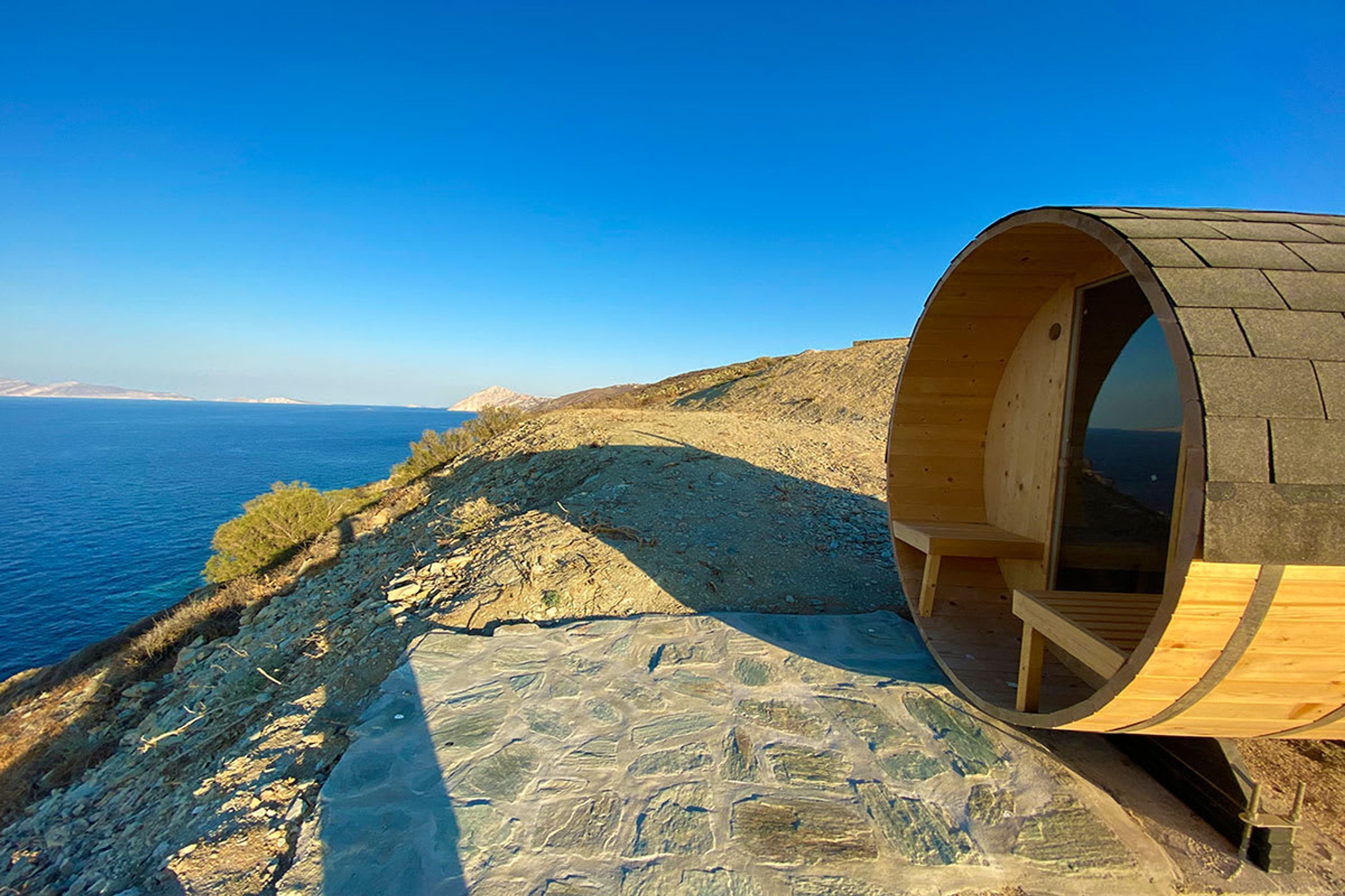 Uma cabana de madeira com telhado curvo, com vista para a paisagem costeira.