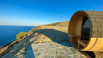 Uma cabana de madeira com telhado curvo, com vista para a paisagem costeira.