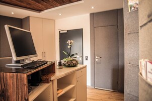 Um espaço de escritório moderno com uma escrivaninha de madeira, um computador e um vaso com flores.