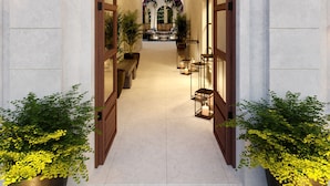 Uma entrada imponente com um arco, um candelabro e plantas em vasos.