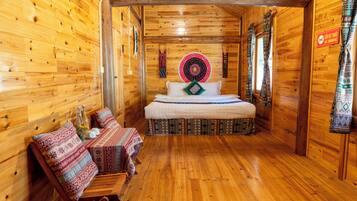 Quarto de cabana de madeira com cama, duas cadeiras e uma mesa.