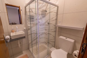 Chuveiro, secador de cabelo, toalhas de banho, papel higiênico