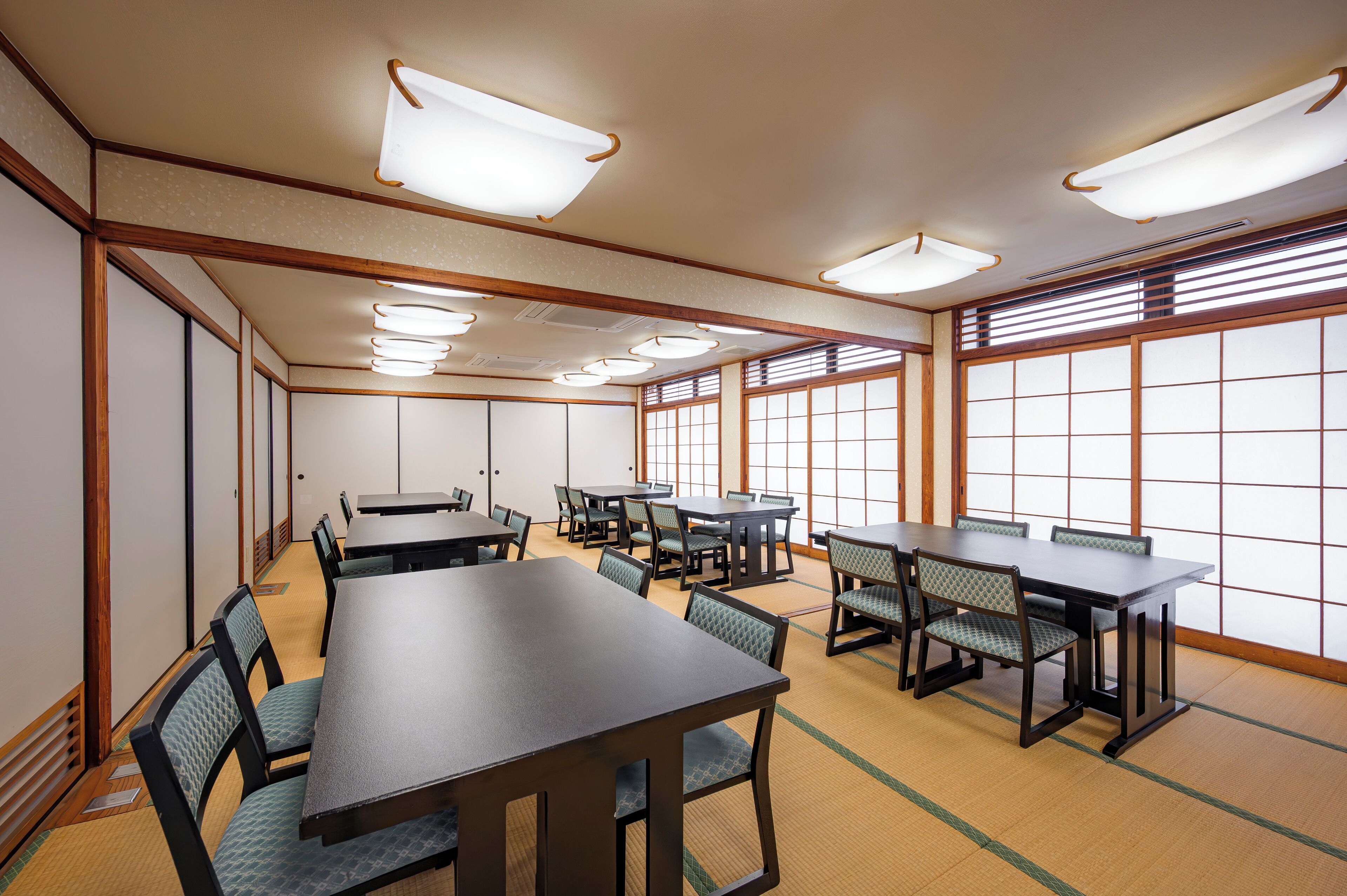 Uma sala de reuniões tradicional japonesa com tatames, mesas baixas e cadeiras.