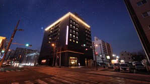Um edifício moderno com janelas iluminadas e um céu noturno estrelado.