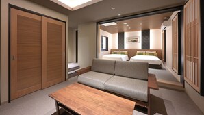 Quarto de hotel com sofá, mesa de madeira e cama com duas almofadas.