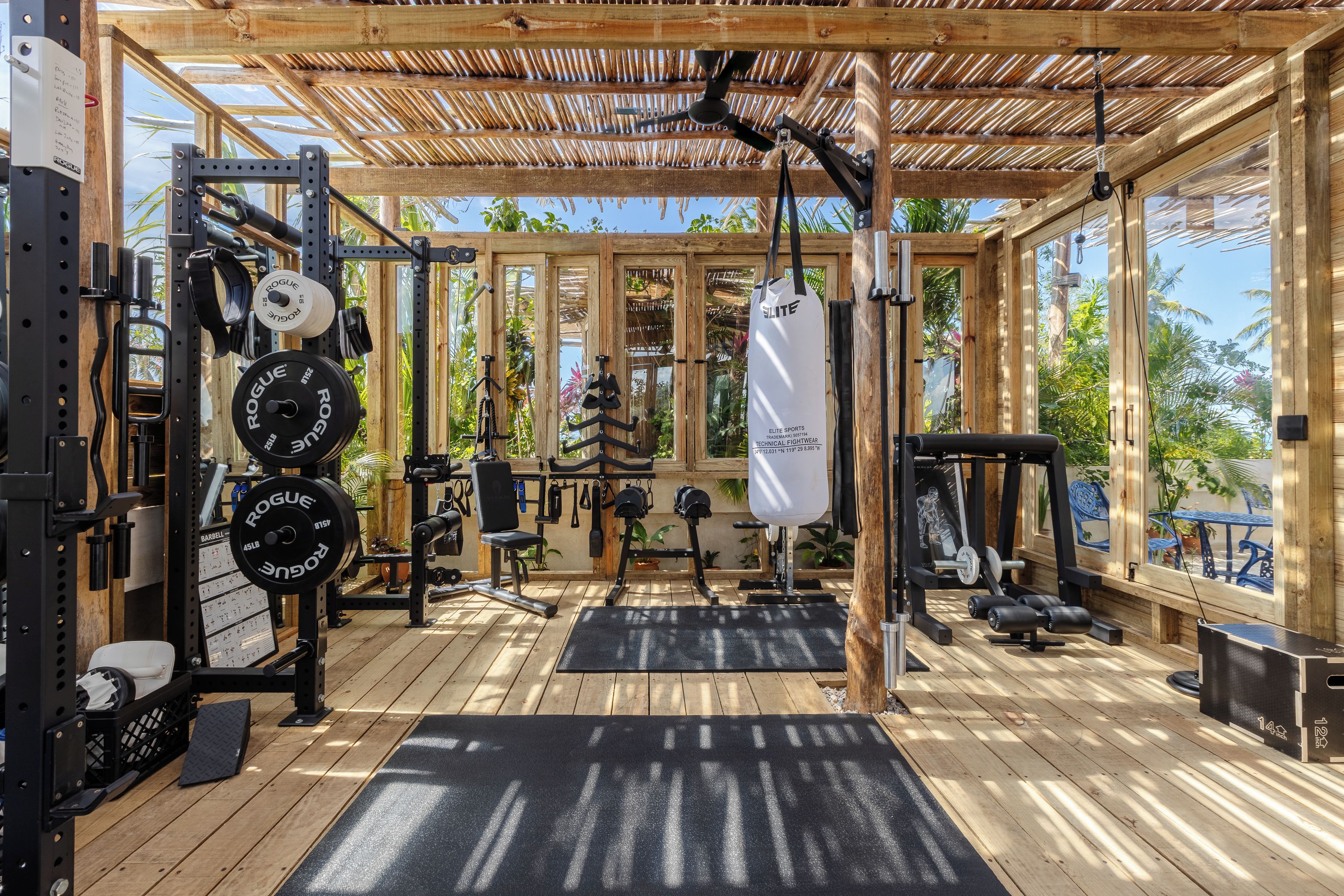 Ginásio ao ar livre coberto com diversos equipamentos de exercício, incluindo estações de musculação e um saco de pancada.