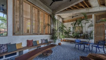 Um espaço amplo e interno com um banco de madeira, cadeiras azuis e uma mesa.