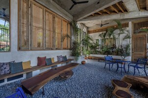 Um espaço amplo e interno com um banco de madeira, cadeiras azuis e uma mesa.