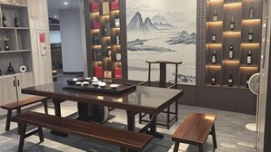 Um restaurante com mesas e bancos de madeira, prateleiras com garrafas e um mural na parede.
