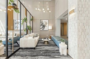 Um lobby moderno com um sofá, cadeiras, uma mesa de centro e uma grande pintura abstrata.