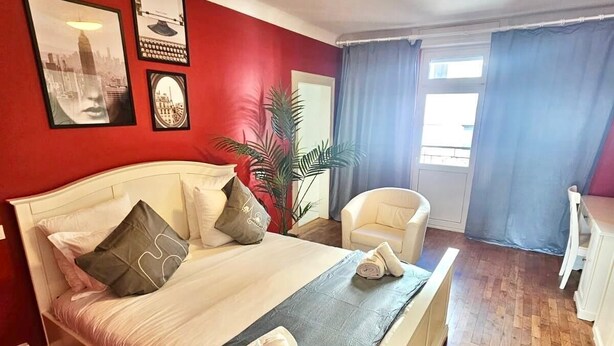 Quarto bem arrumado com uma cama grande, uma cadeira e uma escrivaninha.