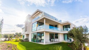 Uma casa moderna de dois andares, com amplas janelas de vidro, telhado plano e um jardim bem cuidado.