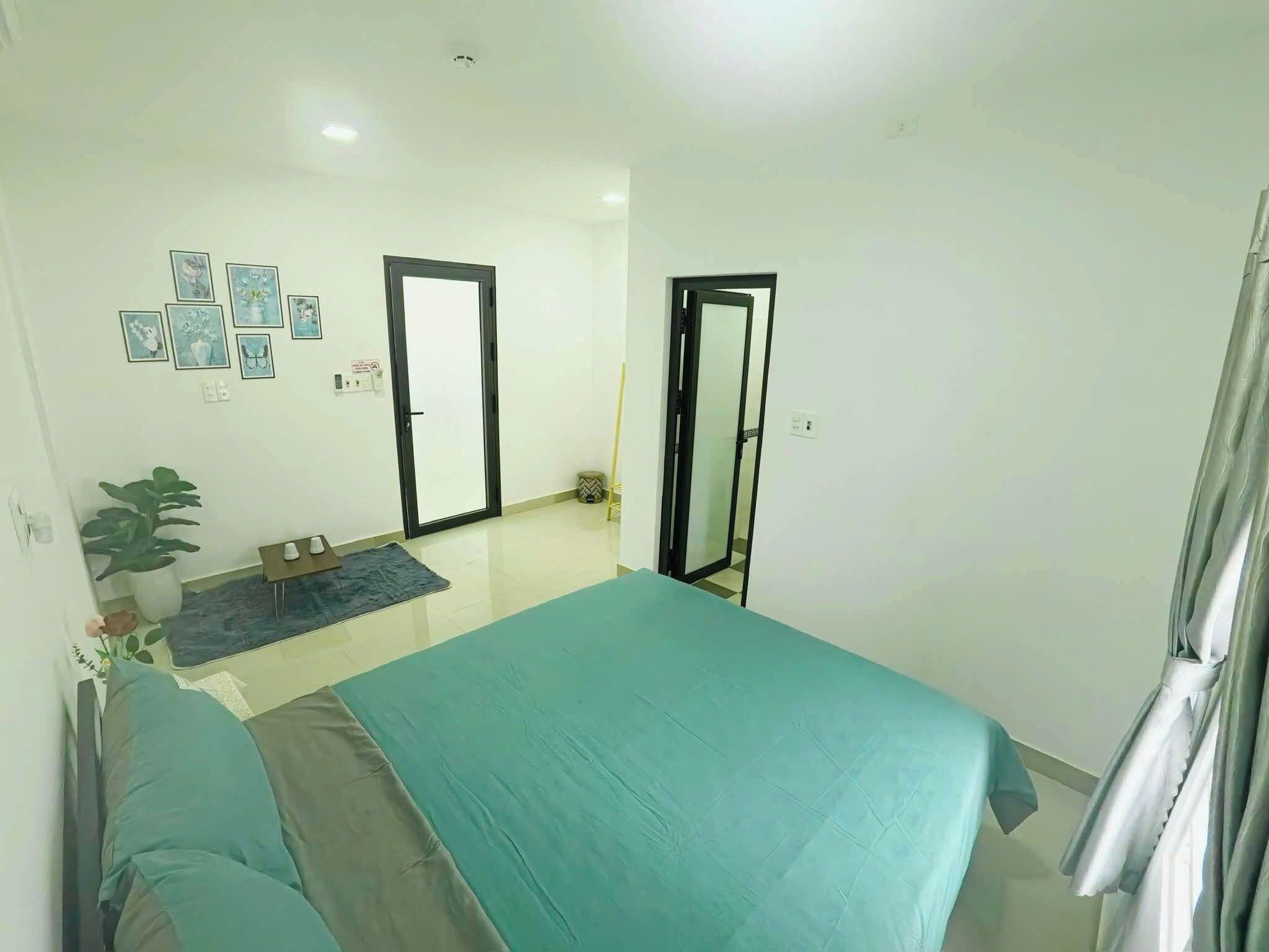 Quarto com cama, planta em vaso e uma pequena mesa com sapatos.