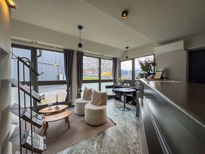 Uma sala de estar moderna com uma janela grande, um espaço de jantar e uma escada.