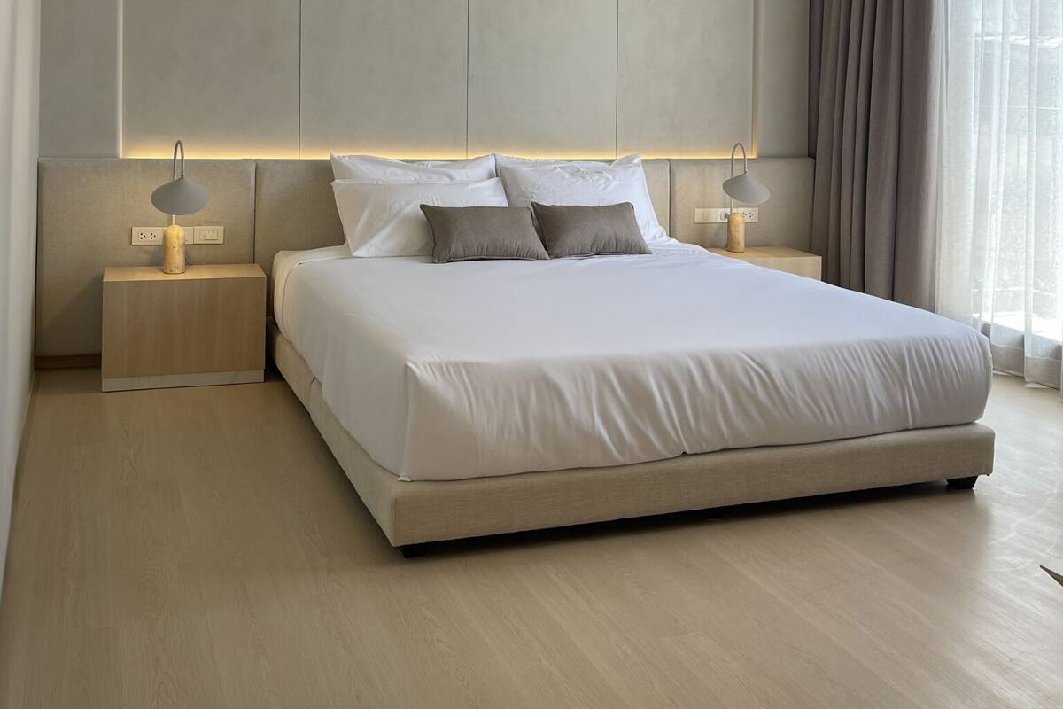 Quarto moderno com uma cama grande, mesas de cabeceira e painel de cabeceira.