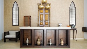 Quarto com um armário de madeira, duas luminárias pendentes e uma pequena mesa com uma chaleira.
