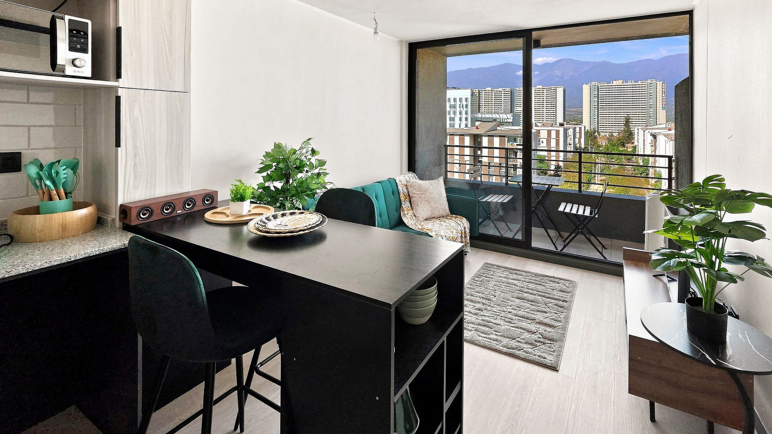 Cozinha moderna com área de refeições, uma grande janela com vista para a cidade e uma varanda com mobiliário de exterior.