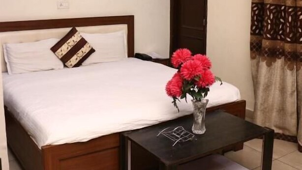 Um quarto com cama, mesa de cabeceira, ventilador de teto, um quadro na parede e um aparelho de ar condicionado.
