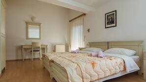 Quarto com cama, escrivaninha, cadeira, espelho e janela com cortinas.