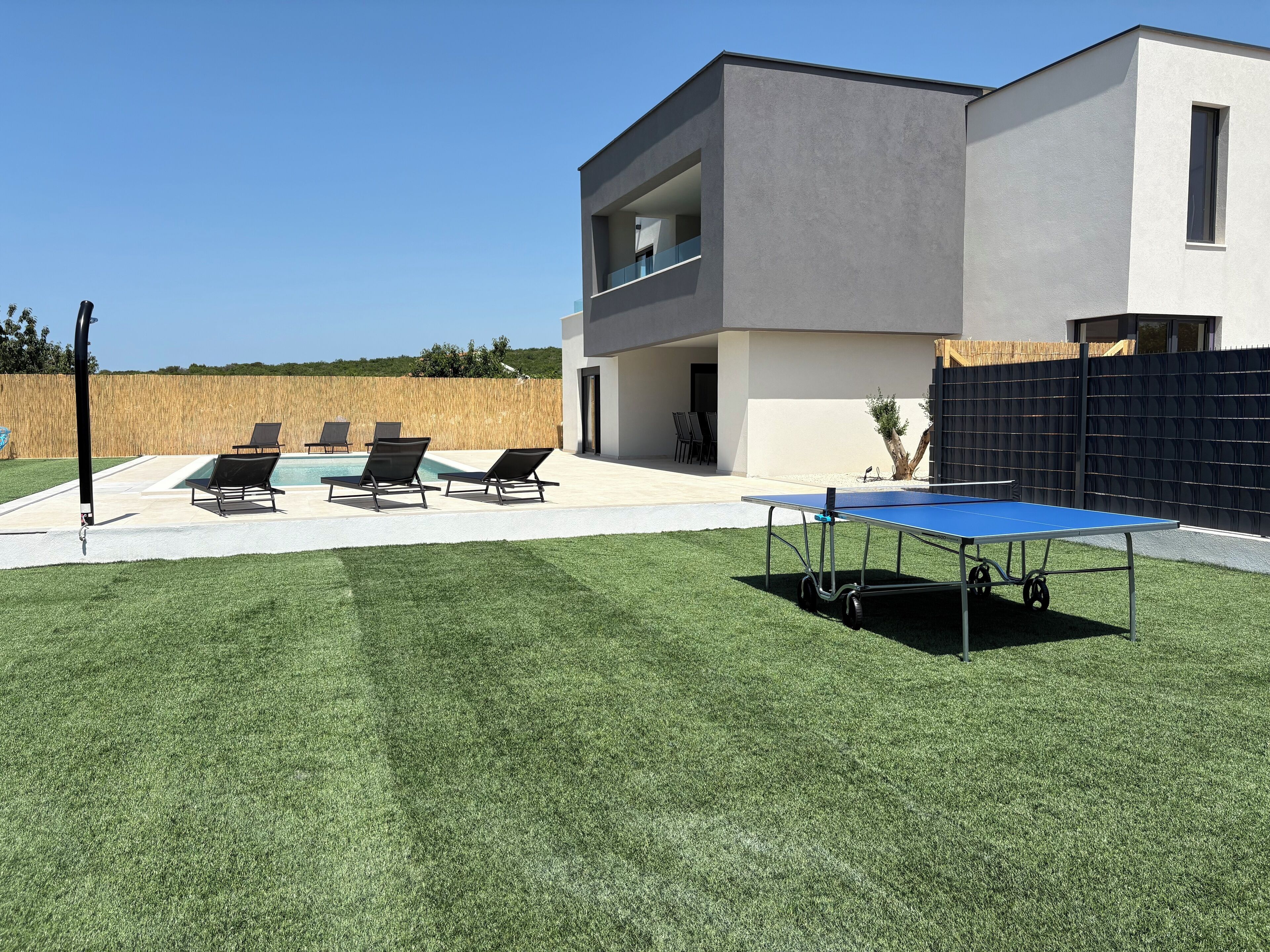 Uma área externa moderna com piscina, espreguiçadeiras e mesa de pingue-pongue.