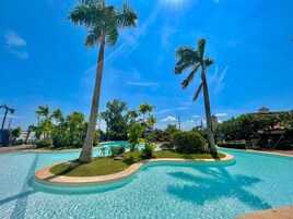 Uma piscina rodeada por palmeiras e um céu azul límpido.