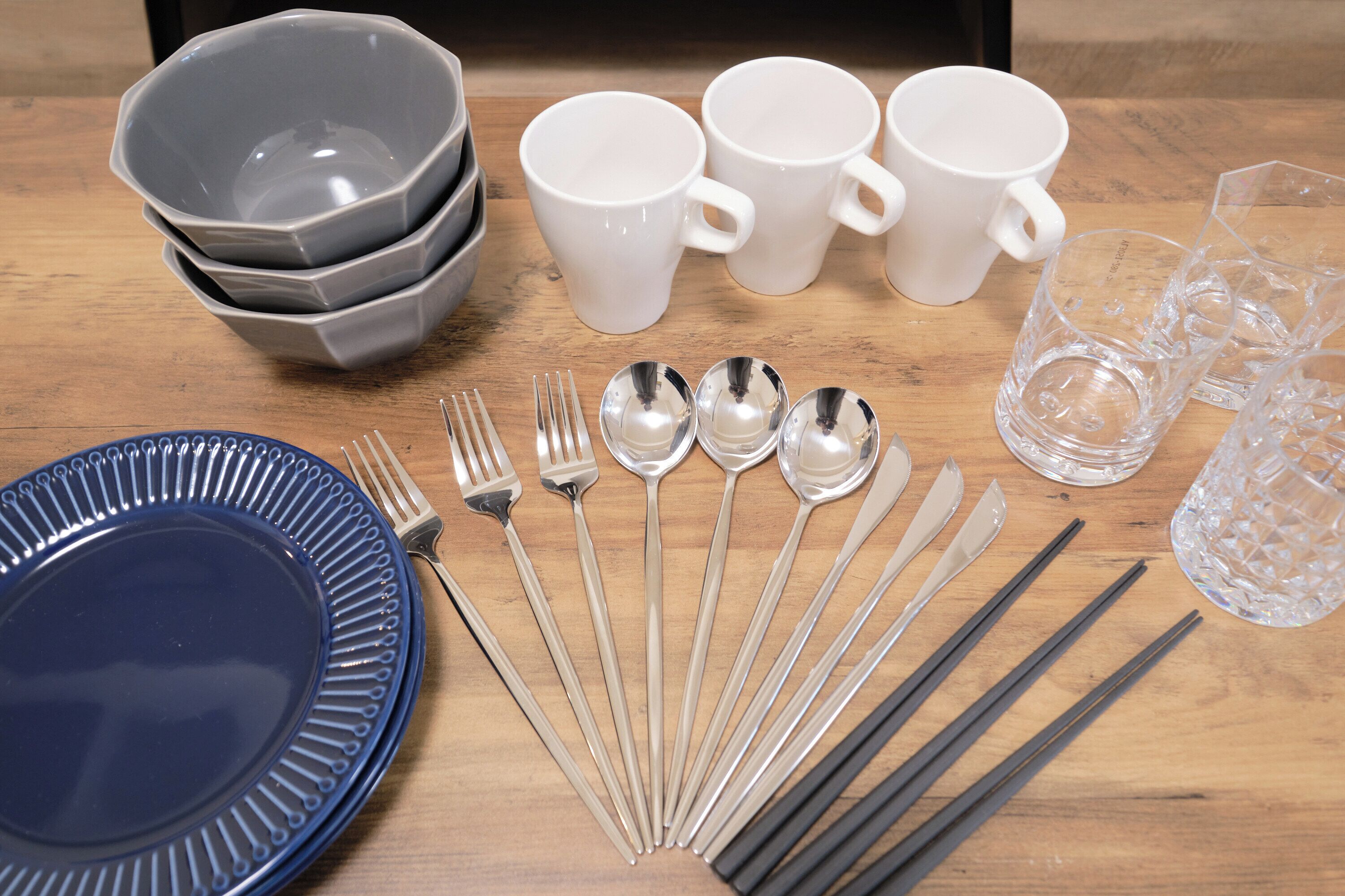 Uma mesa posta com pratos, tigelas, xícaras, talheres e copos.