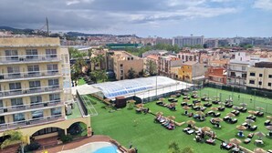 Um hotel com piscina no terraço, quadra de tênis e uma ampla área coberta.