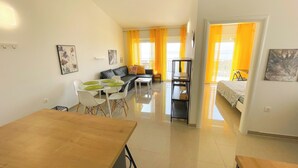 Uma sala de estar moderna com um sofá, uma mesa de jantar com cadeiras e uma pequena mesa lateral.