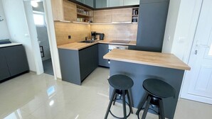 Uma cozinha moderna com bancada de madeira, banquetas pretas e eletrodomésticos embutidos.