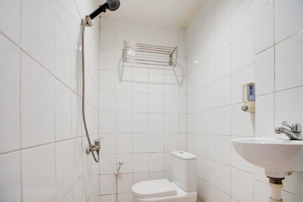 Um banheiro pequeno com azulejos brancos, contendo vaso sanitário, pia e chuveiro.